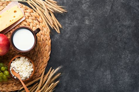 해피 샤부엣 Shavuot 전통 종교 유대인 축하의 배경 우유와 치즈 잘 익은 밀과 과일 오래된 어두운 회색 배경 위에 유제품
