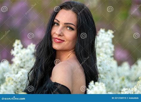 Woman With Long Black Hair Posing In A Garden Background With
