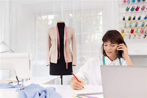 바느질 스튜디오에서 일하는 젊은 여성 드레스 메이커 사업가가 고객과 전화통화를 하고 있습니다 맞춤형 테일러링 민간 기업 취미와