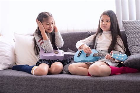 소파에 앉아 우쿨렐레를 함께 연주하는 두 어린 소녀 스튜디오에서 행복한 느낌 흐릿한 빛 주위 개념에 대한 스톡 사진 및 기타 이미지 Istock