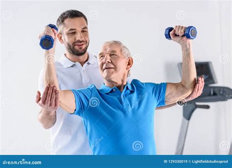 Portrait Of Rehabilitation Therapist Assisting Senior Man Stock Image