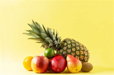 Surtido de frutas tropicales sobre fondo amarillo piña manzana