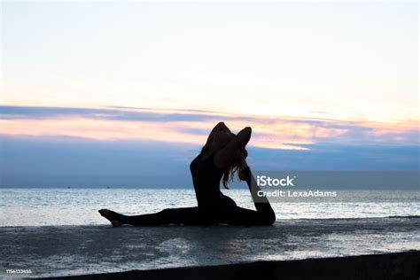 바다에 일출에 요가 분할을하고 아름다운 몸을 가진 인식 할 수없는 세노아르 여자 요가 포즈의 실루엣 건강한 생활방식에 대한 스톡