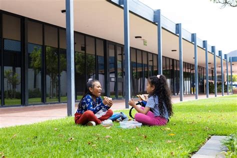Premium Photo Two Biracial Girls Are Enjoying Lunch On The Grass In