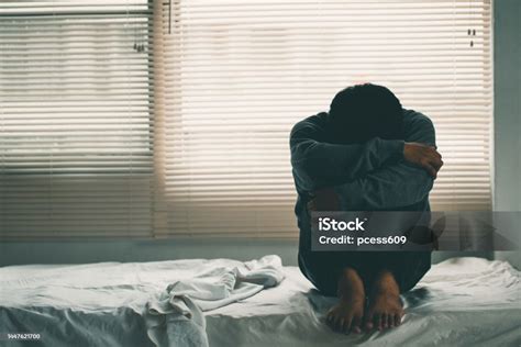우울한 남자는 직장을 잃고 어두운 곳에서 어두운 창문 근처의 침대에 혼자 앉아 상심하고 어두운 환경 Ptsd 정신 건강 및