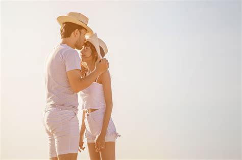 젊은 부부는 해변에서 사랑에 남자 친구 키스 여자 친구 에 이마 행복 일몰 야외에서 낭만적 인 아시아 여름 아침 빛 모자 허니문