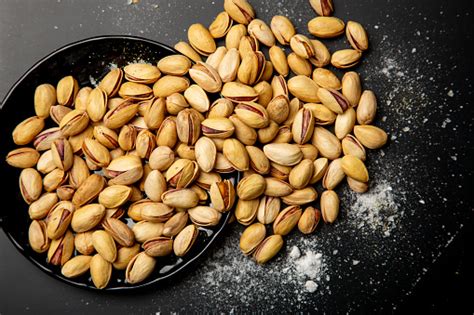 검은 색 배경에 거친 바다 소금을 가진 껍질에 피스타치오 너트 맥주 애피타이저 소금에 절인 견과류 컨셉은 맥주를 위한 간식입니다