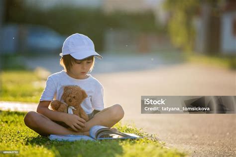 아름 다운 아이 보가 거리에서 테 디 베어 화려한 일몰 빛 함께 앉아 책을 읽고 거리에 대한 스톡 사진 및 기타 이미지 거리