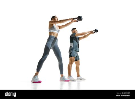 Dynamic Portrait Of Fit Man And Woman Performing Kettlebell Squat