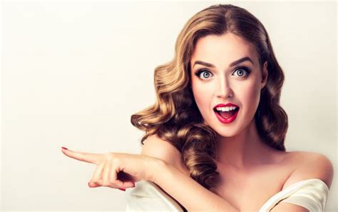 زن تعجب نمایش محصول دختر زیبا با موهای مجعد اشاره به سمت ارائه محصول