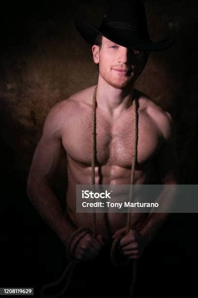 정의된 Pecs와 식스팩 복근 로프를 들고 있는 근육질의 팔을 보여주는 모자를 쓰고 있는 잘생긴 카우보이 가수에 대한 스톡 사진