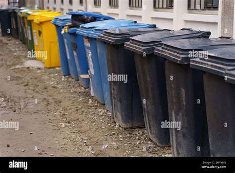 Rows Of Garbage Cans Of Different Colors In An Alley In The City Center