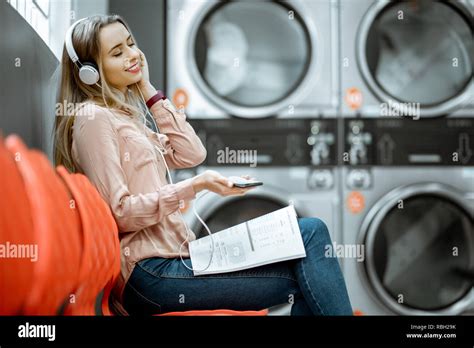 Young Woman Enjoying Music Waiting For The Clothes To Be Washed Sitting