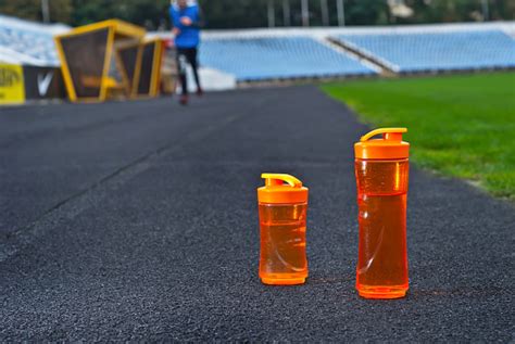 검은 색 러닝머신에 오렌지 물병 건강한 라이프 스타일의 개념 병 근처에 텍스트 공간을 복사하고 배치합니다 운동 선수는 경기장의 배경에서 마십니다 개념에 대한 스톡 사진 및