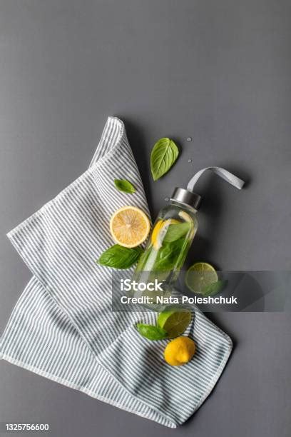 회색 배경에 과일 라임 레몬 바질 잎 줄무늬 수건이 있는 물 한 병이 놓여 있습니다 건강과 웰빙 개념 0명에 대한 스톡 사진 및