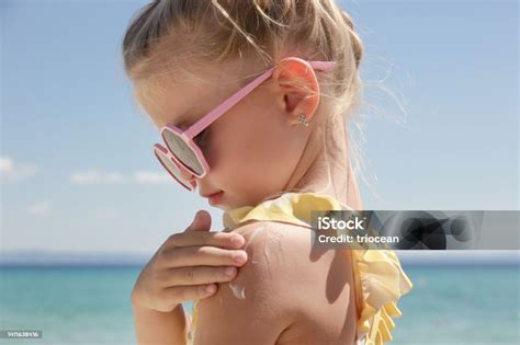 해변에서 자외선 차단제 보호 크림을 바르는 귀여운 4 세 소녀 여름 방학 동안 태양으로부터 어린이를 보호하기위한 태양 차단 로션 여행 시간 동안 어린이 피부 관리 4 5세에