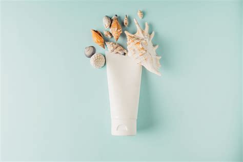 파란색 배경에 조개껍데기가 달린 흰색 플라스틱 튜브 크림 화장품 및 화장품 제품에 대한 모형 해상 및 여름 개념 태양과 바람으로부터 Spf 보호 0명에 대한 스톡 사진 및