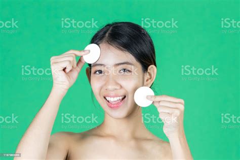 예쁜 아름다움 젊은 아시아 여자 녹색 고립 된 배경 위에 면 패드와 그녀의 얼굴을 청소 건강 한 피부와 화장품 컨셉 건강관리와
