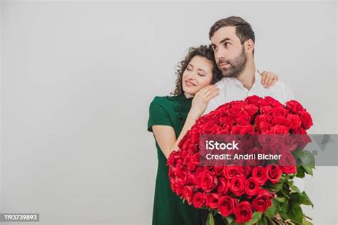 행복한 우아한 부부는 흰색 배경에 포옹하고 미소짓고 있습니다 남자는 장미를 들고있다 2명에 대한 스톡 사진 및 기타 이미지