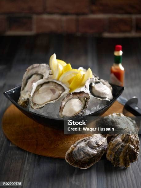 Seafoodlive Australian Oyster는 어두운 배경의 커팅 보드 측면보기에서 격리 된 요리에서 제공됩니다 0명에