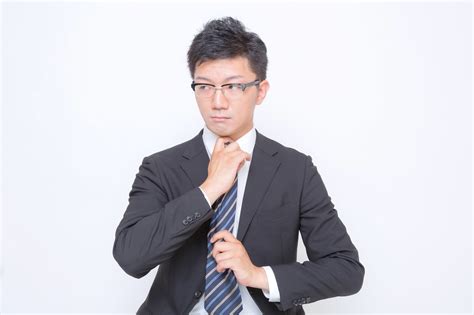 ネクタイを締め直す眼鏡をかけたビジネスマン｜ぱくたそフリー素材