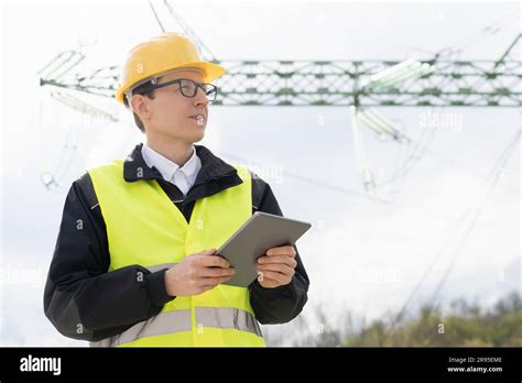 Engineer With Digital Tablet On A Background Of Power Line Tower Stock