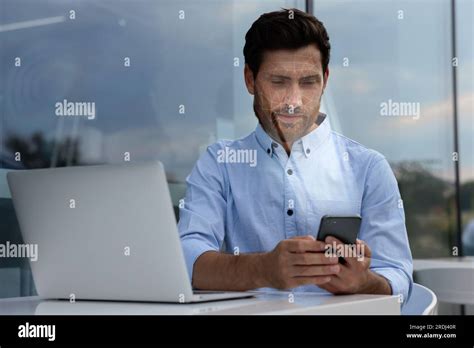 Man Using Smartphone With Facial Recognition System In Cafe Security