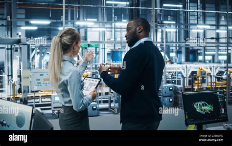Car Factory Office Female Engineer Talks With Male Scientist Use Tablet Computer To Design