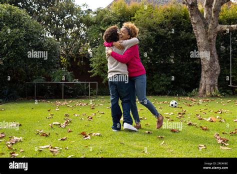 Happy African American Mother And Son Embracing In Garden Stock Photo