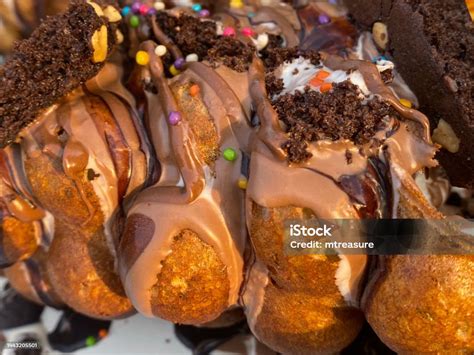 초콜릿 브라우니 조각 설탕 뿌리 카라멜 토피 소스 쿠키 과자 초콜릿 시럽으로 덮인 아이스크림이 있는 판지 상자에 담긴 버블 와플 콘의 전체 프레임 이미지 길거리 음식 시장