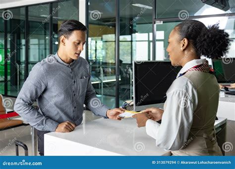 Asian Passenger Is Receiving His Boarding Pass From The Airline Ground Crew At Check In Counter