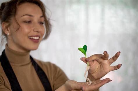 Retrato De Uma Mulher Sorridente Segurando Uma Planta Foto Premium