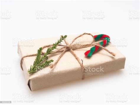 A 현재 또는 거친 갈색 재활용 종이 포장 하 고 흰색 배경에 고립 된 파인 지점 및 사탕 지팡이와 갈색 대 마 밧줄 리본으로
