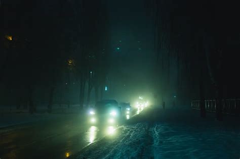 안개가 낀 날씨 밤 안개 도로에서 시야가 좋지 않습니다 자동차의 움직임 교통 체증 젖은 미끄러운 아스팔트 자동차 헤드 라이트 빛의 광선 도로에 눈과 얼음 도시 거리 가로등에