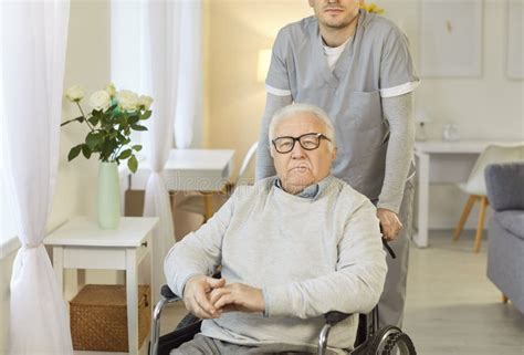 Portrait Young Nurse Senior Disabled Patient Wheelchair Looking Camera