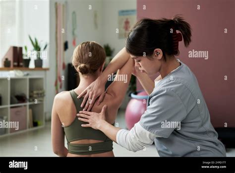 Physical Therapist Helping Patient With Shoulder Pain In Clinic