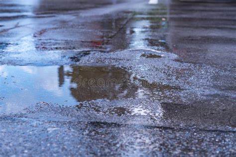 Close Up Puddle On The Asphalt With Reflections After The Rain In City
