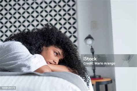 젊은 곱슬 여자는 그녀의 목욕 가운을 입고 그녀의 침대에 누워 매우 슬픈 과 Covid에 의해 생성 된 외로움과 우울증의 태도