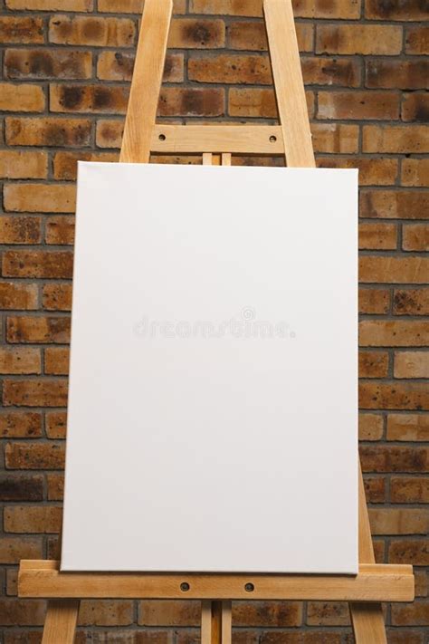 White Canvas On Wooden Easel And Copy Space On Brick Wall Background