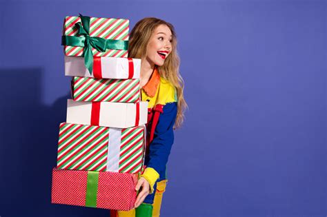 활기찬 보라색 배경 앞에 형형색색의 선물 더미를 들고 흥분과 축제의 기쁨을 표현하는 쾌활한 젊은 여성 16 17 살에 대한 스톡 사진 및 기타 이미지 Istock