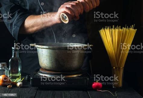 요리사는 야채를 배경으로 이탈리아 파스타를 준비합니다 식당 주방에서 냄비에 고추를 붓는 요리사 손의 클로즈업 건강한 생활방식에