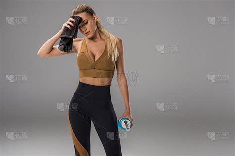 运动的年轻女子用毛巾在灰色的额头上擦汗