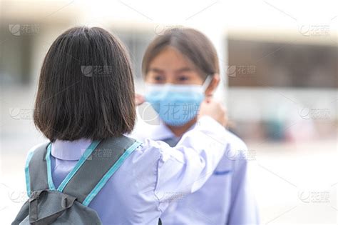 在新冠肺炎疫情形势好转后，孩子们穿着校服，戴着防护口罩互相上学。回到学校概念库存照片