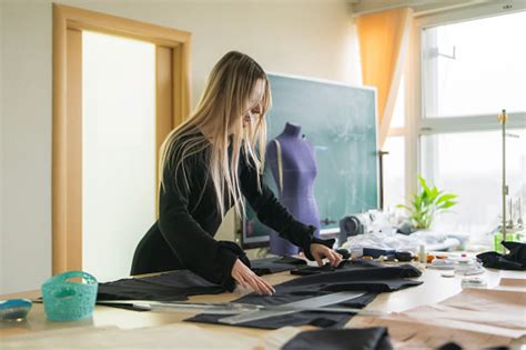 숙련된 재단사는 밝고 조직적인 작업장에서 다양한 직물과 재봉 도구로 둘러싸인 자신의 작업에 집중하고 있습니다 25 29세에 대한 스톡 사진 및 기타 이미지 Istock