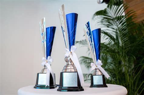 Três Troféus Na Mesa De Círculo Branco Com Fundo De Folha De árvore No