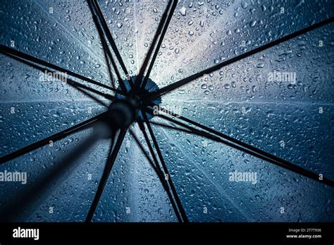Raindrops On Open Umbrella Seen From Below Against City Lights At Night