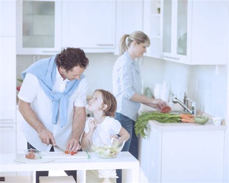 Padre E Hija Que Miran Uno A Mientras Que Prepara La Comida Sana En Cocina Imagen De Archivo
