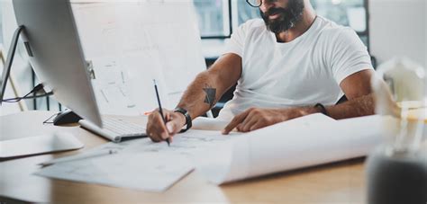 데스크톱 컴퓨터와 현대 로프트 스튜디오 사무실에서 일 하는 눈 안경을 쓰고 수염된 전문 건축가 흐리게 배경입니다 Horizontalcropped입니다 전자 학습에 대한 스톡