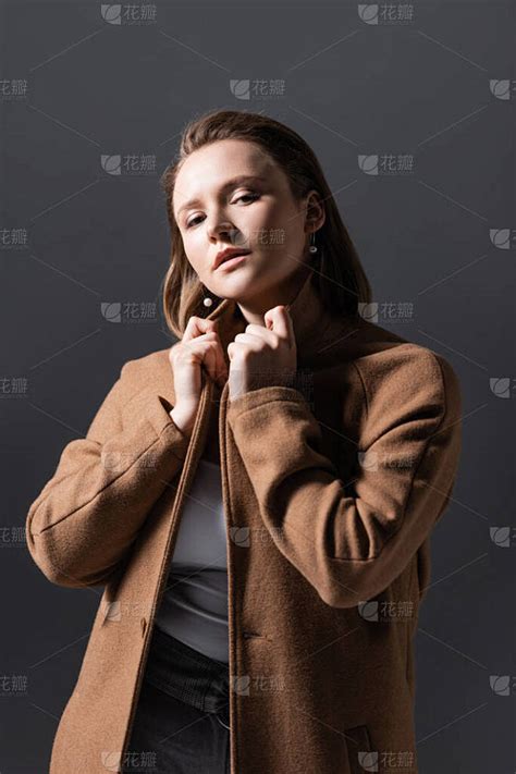 自信、美丽、超重的女孩一边摸领子，一边看着灰色的相机