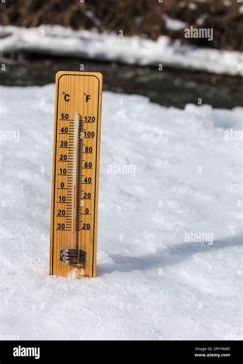 Wooden Thermometer Standing In Ice On Partially Frozen River Sun